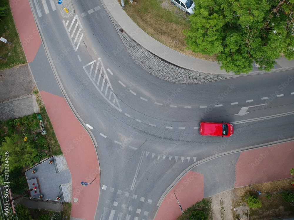 Red car driving across curved intersection in city, aerial view Stock ...
