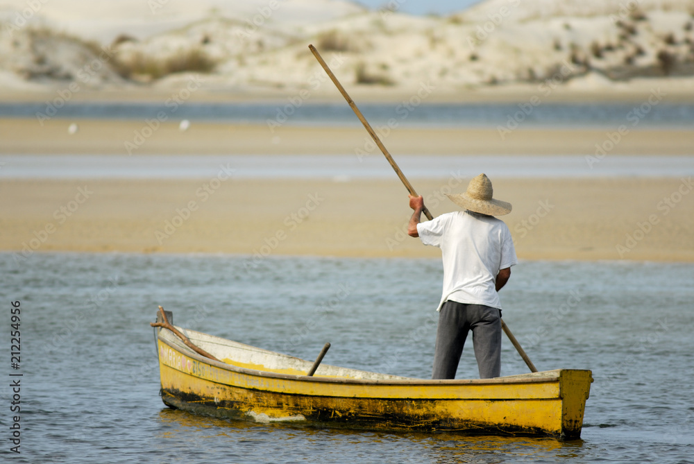 barqueiro de costas atravessando com barco amarelo o rio e dunas de ...