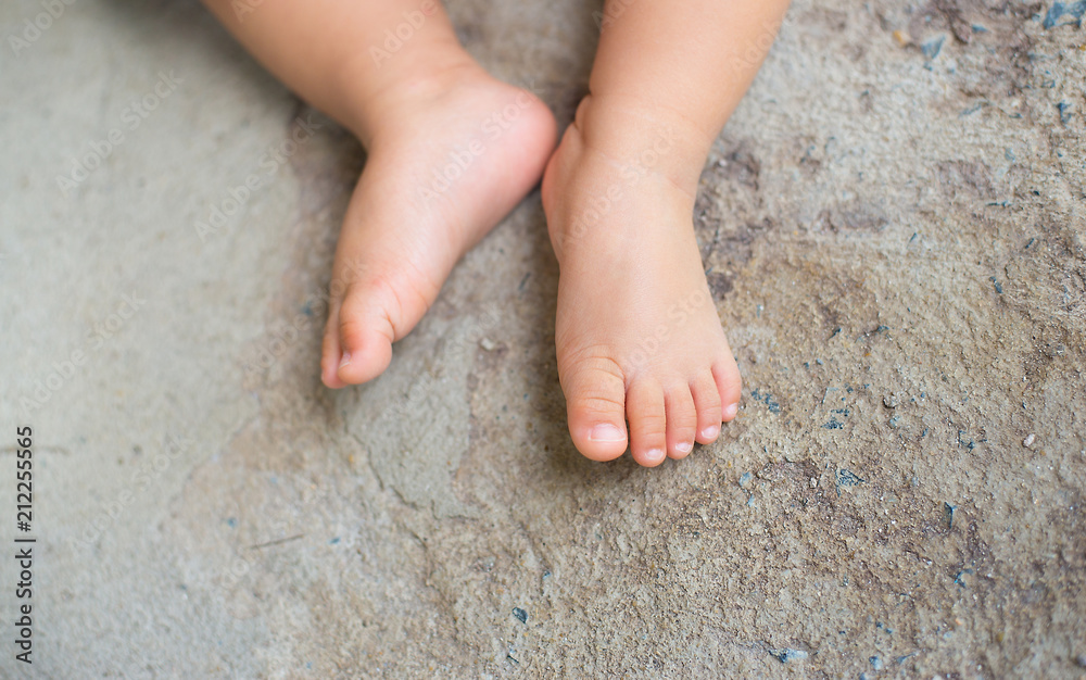 The foot of the child on the concrete floor is old and uneven. Stock ...