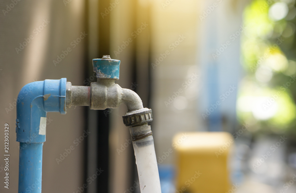 Blue brass water tap with rubber tube attach in the end with sun flares ...