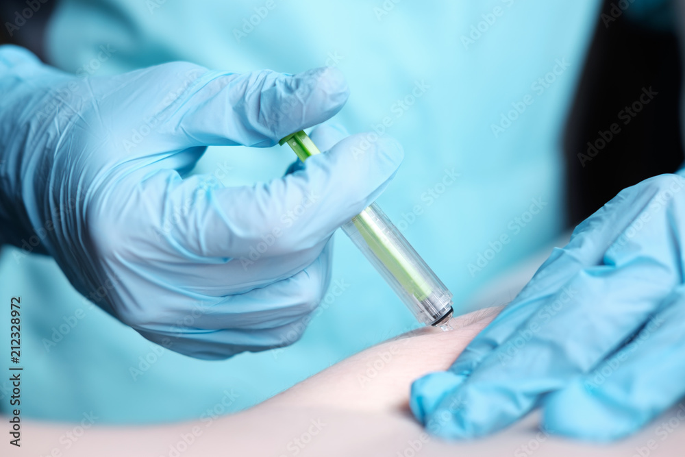 hands of nurse in blue surgical gloves making injection of ...