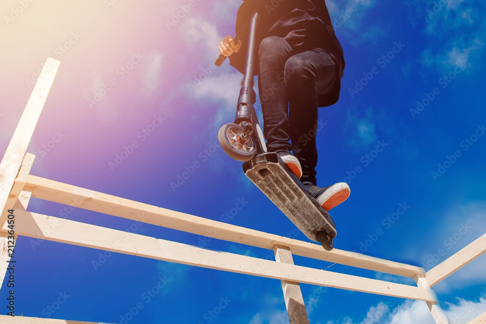 Man riding kick scooter in park ramp and springboards. Background Blue ...