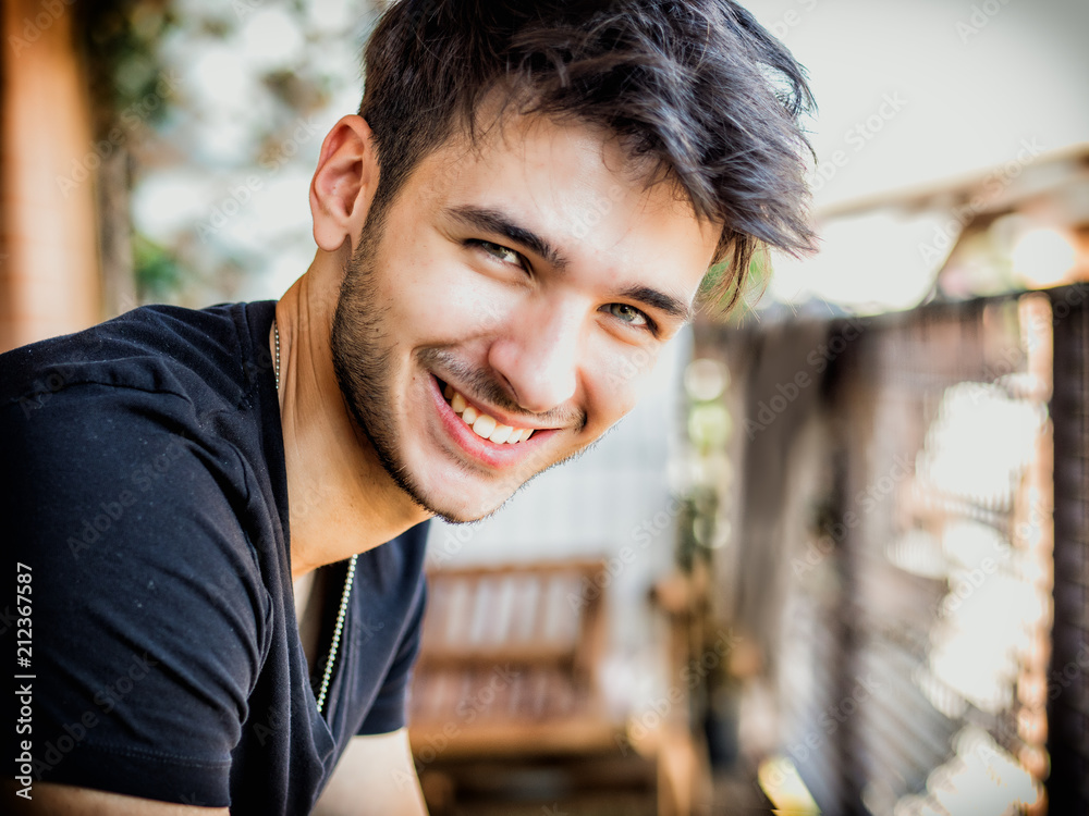 Handsome dark haired, green eyed young man sitting in a balcony ...
