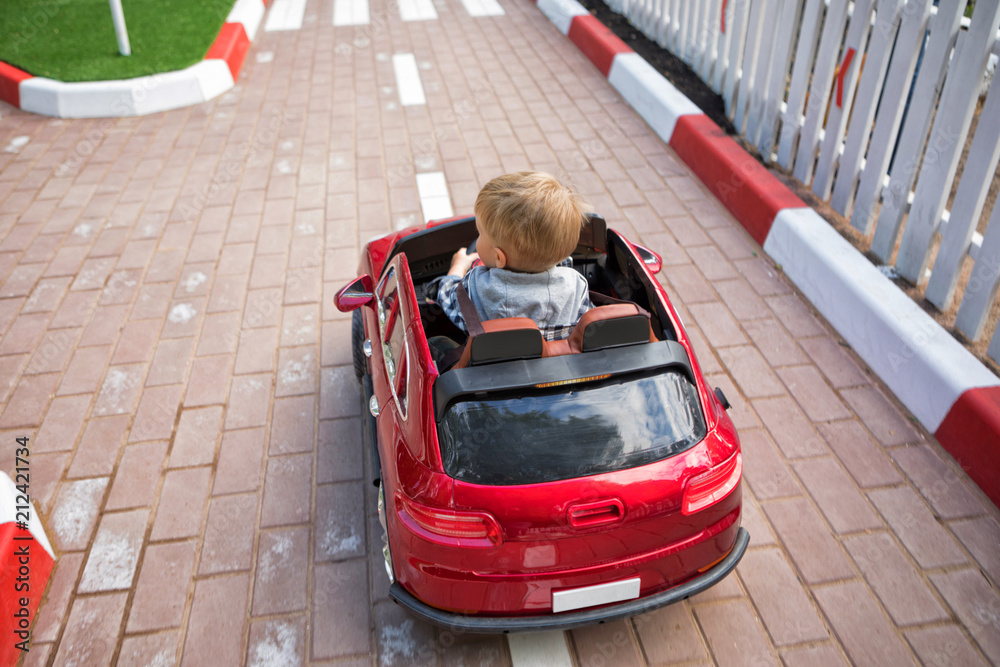 Little kid on a children's electric car is driving on special road for ...