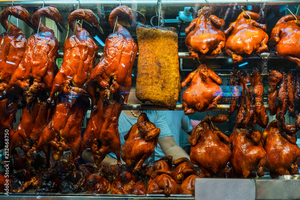 Rows of roast ducks with roast chicken and crispy pork on display at a ...