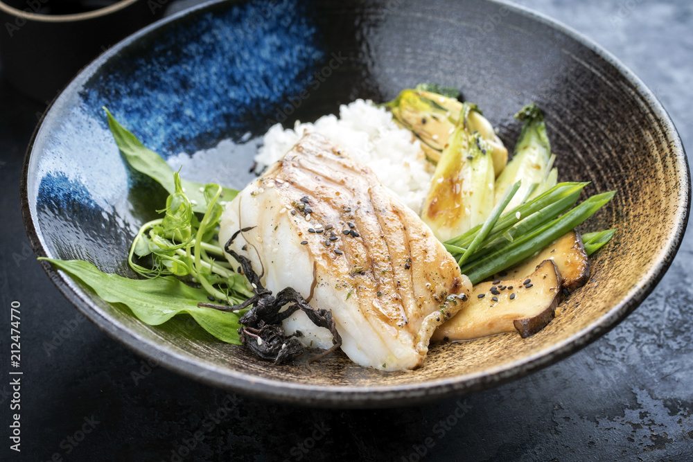 Modern Japanese fried cod fish filet with bok choi and rice as top view ...