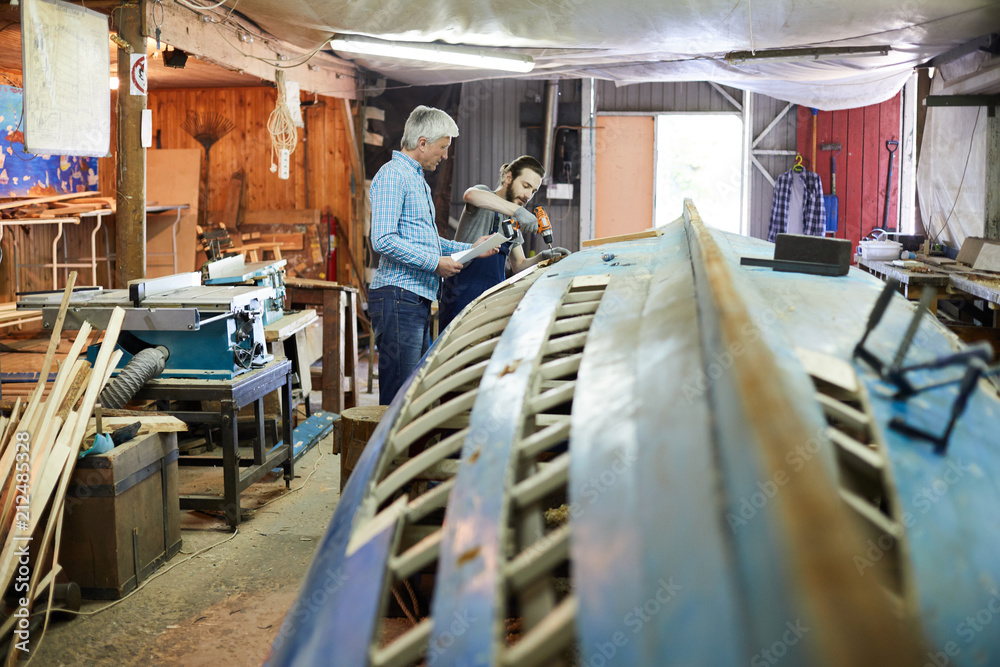 Professional master of shipbuilding giving instructions to his young ...