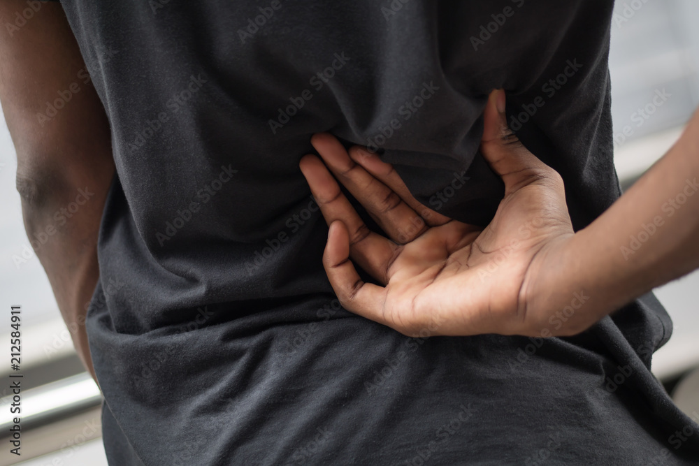 man suffering from back pain; sick african man with back joint pain ...