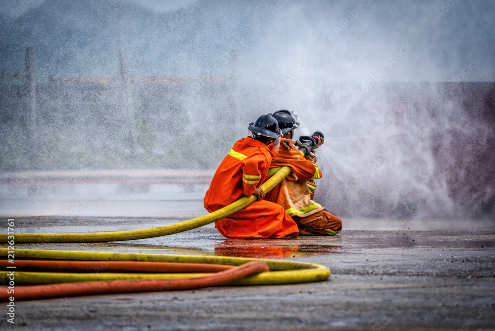 Fireman using water and extinguisher to fighting with fire flame in an ...