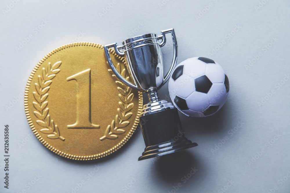 Gold first place winners medal and trophy with a soccer ball. Football ...