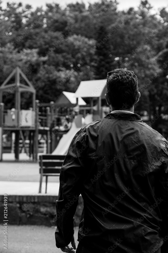 Worried man looking to a empty city playground. Converted to black and ...