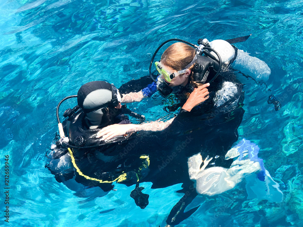 Two divers in black scuba diving suits, a man and a woman with oxygen ...