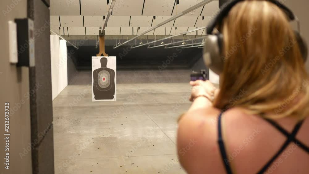 Woman shoots at a target of a man on an indoor gun shooting firing ...
