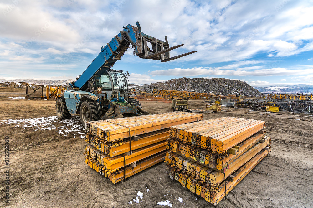 Forklift on a construction site, preparing to raise construction parts ...