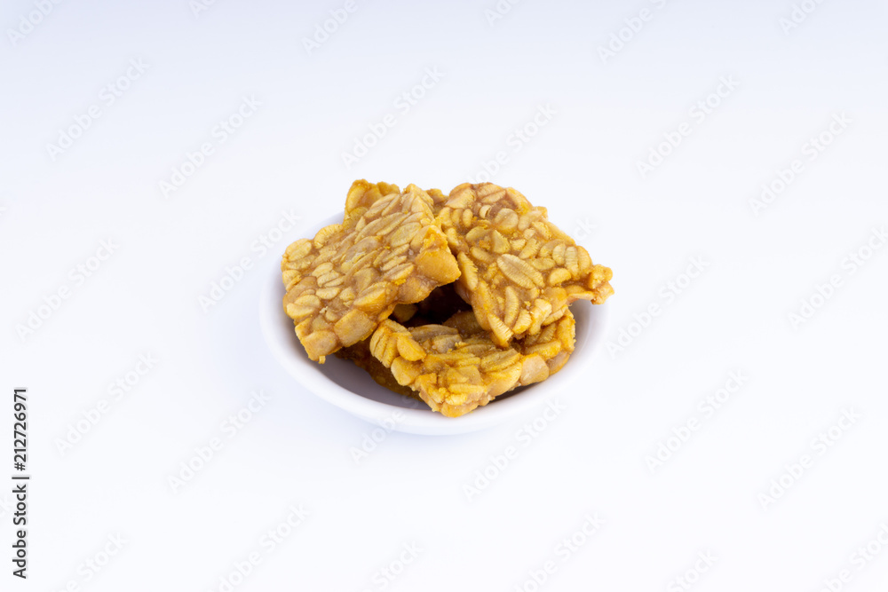Fried tempeh or soybean cake in white bowl over a white background. It ...