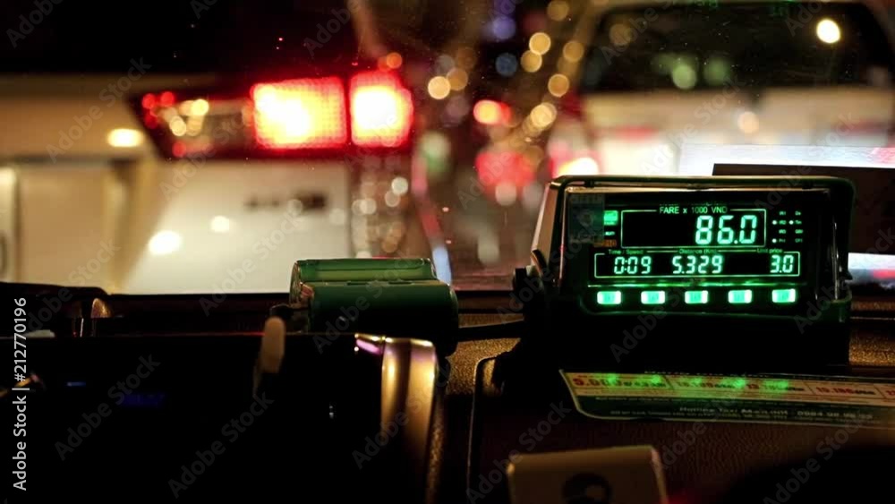Waiting in night city traffic inside taxi car. The digital taxi meter ...