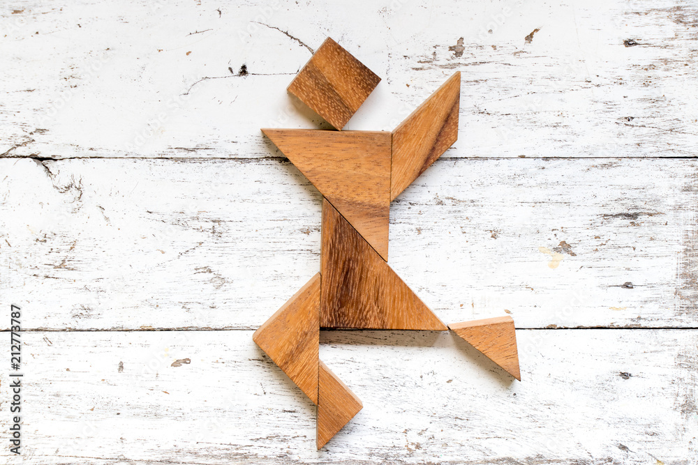 Tangram puzzle in happy running or dancing man shape on old white wood ...