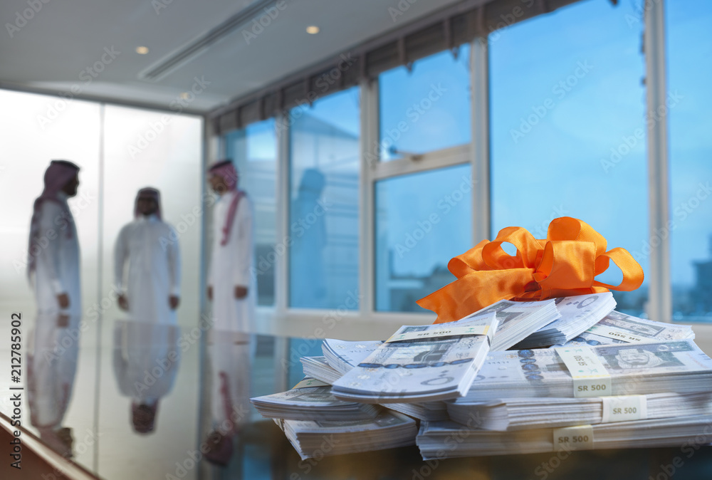 Saudi Arab businessmen in a meeting room with stacks of money on the ...