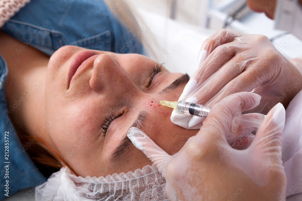 The doctor cosmetologist makes the Rejuvenating facial injections ...