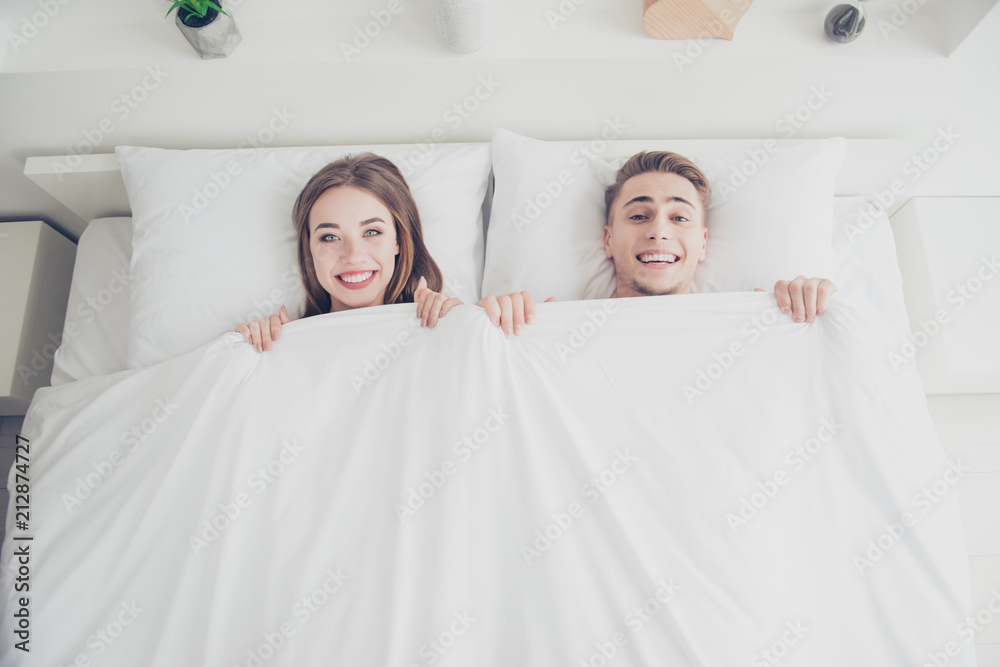 Portrait of young attractive sleepy couple awakening together in bed in ...