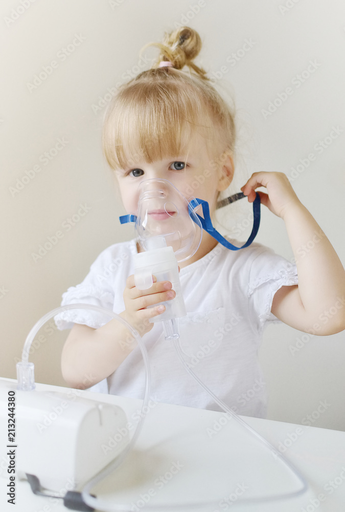 Little girl in a mask for inhalations, making inhalation with nebulizer ...