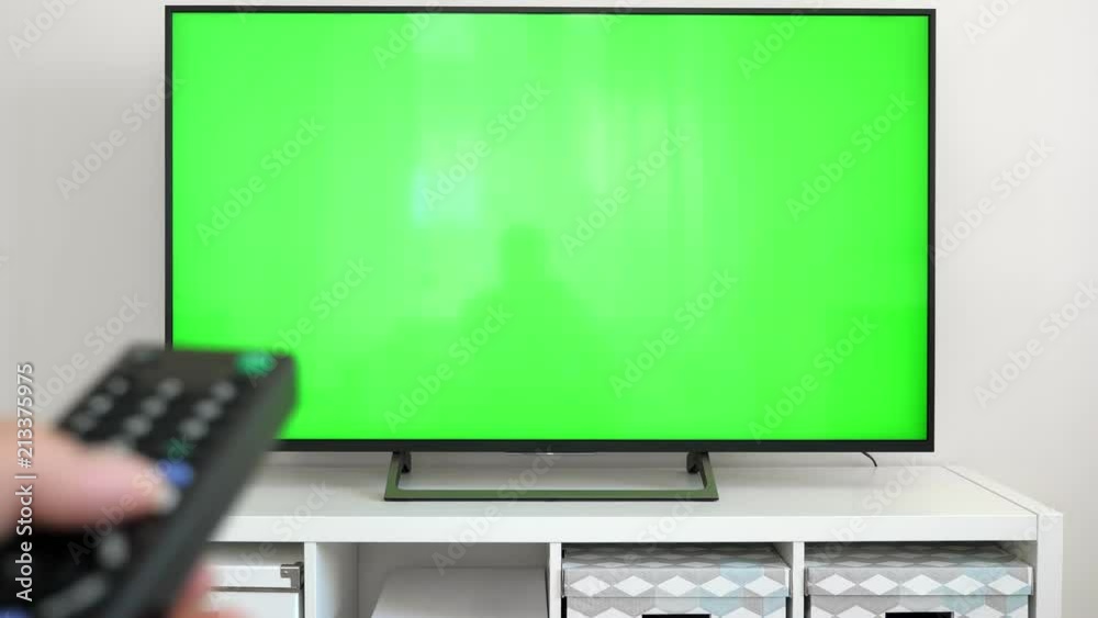 Watching tv with green screen at home interior. Push buttons on remote ...