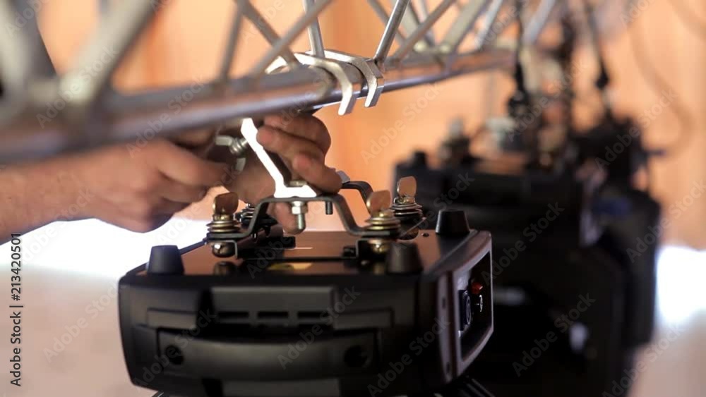 Light technician attaches the spotlight screw to the base of the stage ...