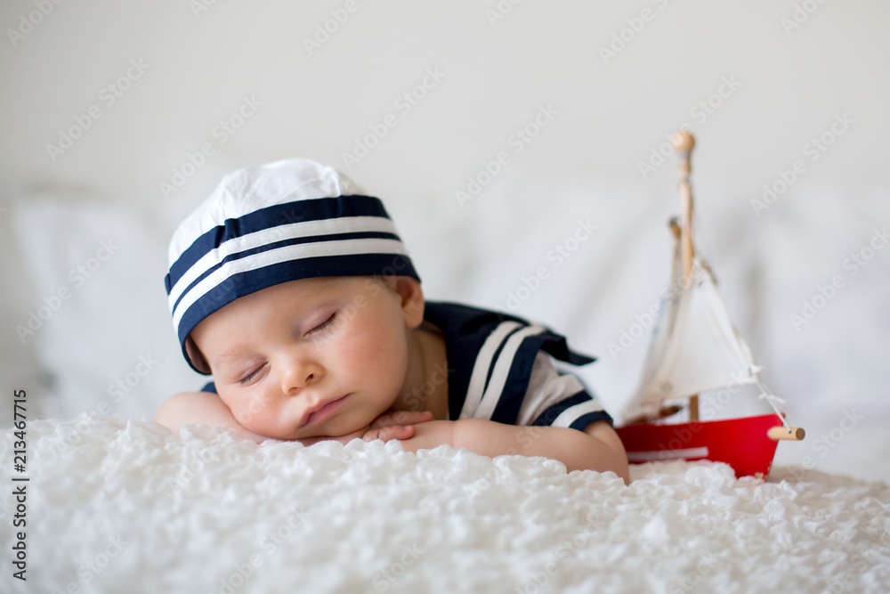 Cute baby boy, dressed in marine clothes, sleeping with wooden boat and ...