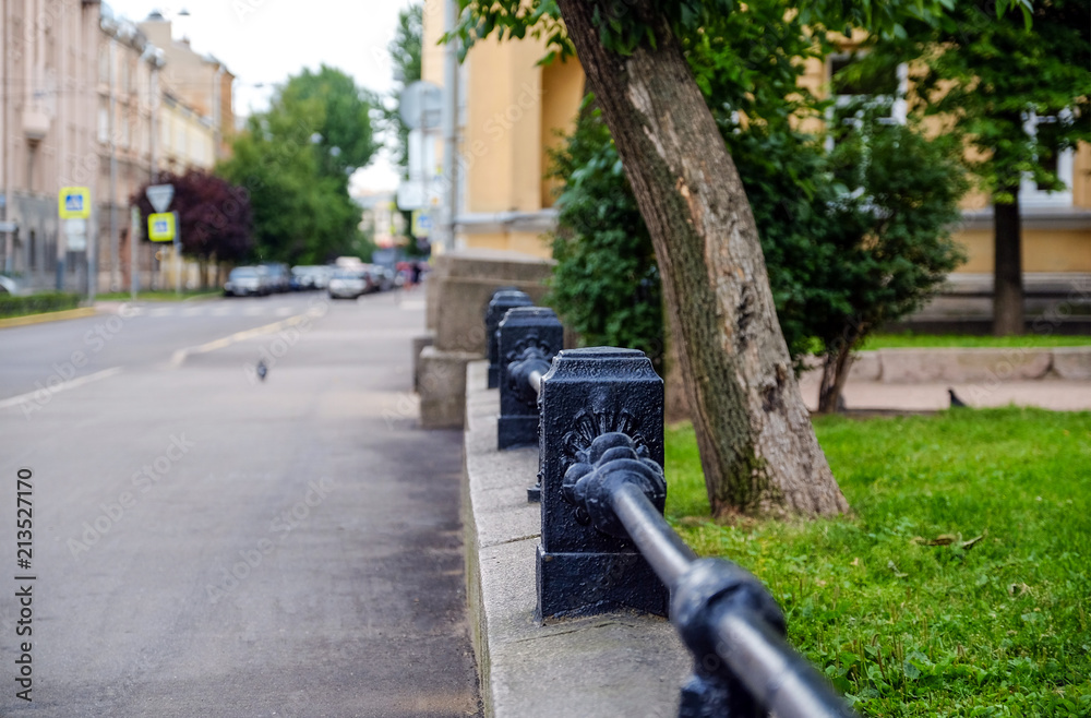 Black, forged, metal railing on a low Sandstone wall recede into the ...
