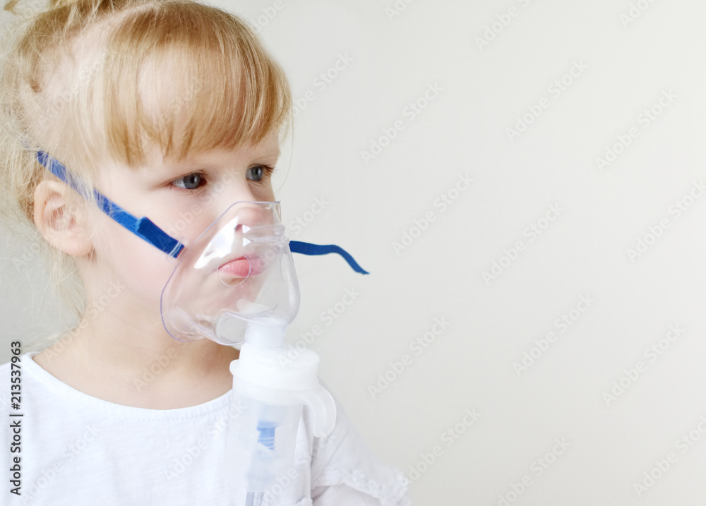 Little girl in a mask for inhalations, making inhalation with nebulizer ...