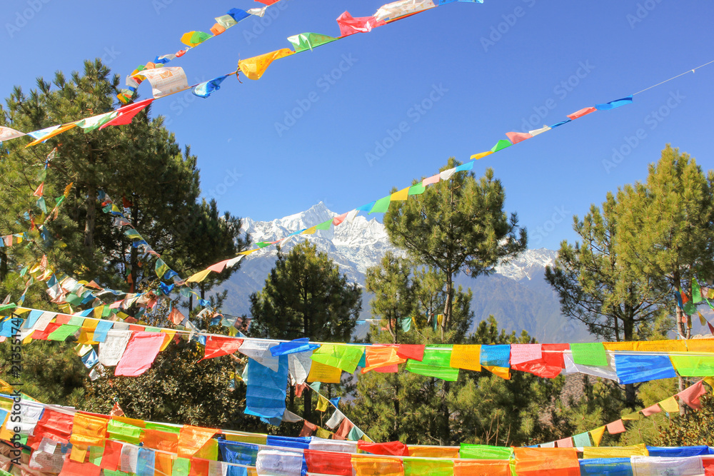 Tibetan prayer flags among trees with Meili Xue Shan mountain range on ...
