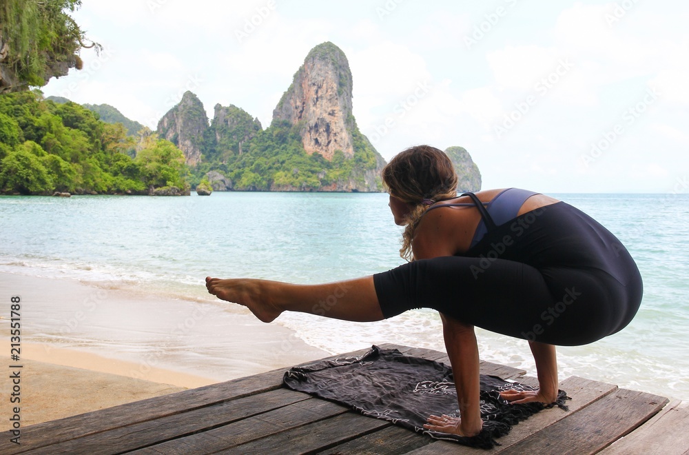 Young woman practicing yoga in titibasana. Female yogi on firefly pose ...