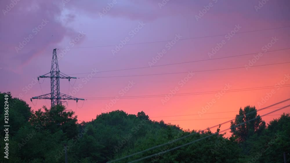 Electricity pylons, power lines and trees silhouetted against sunset ...