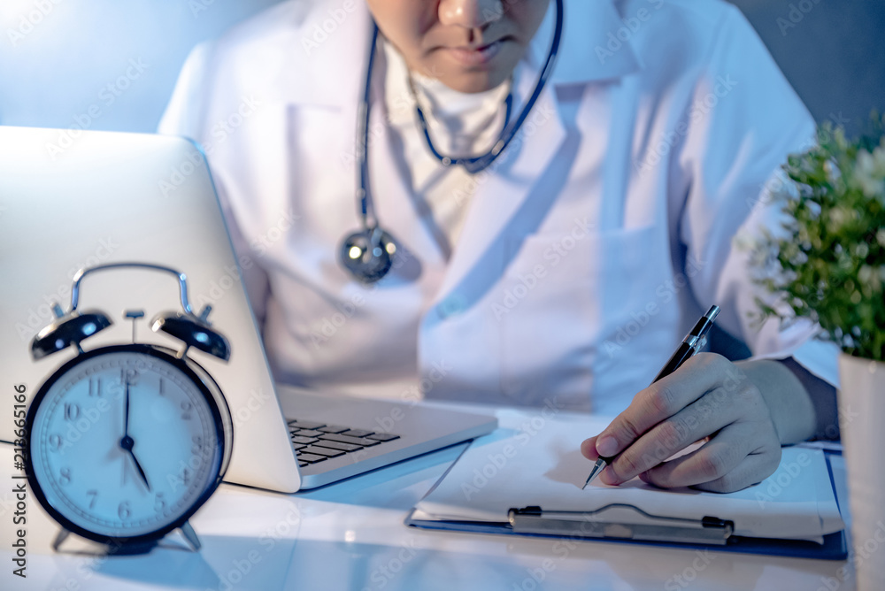 Male Asian doctor working with laptop computer writing on medicine ...