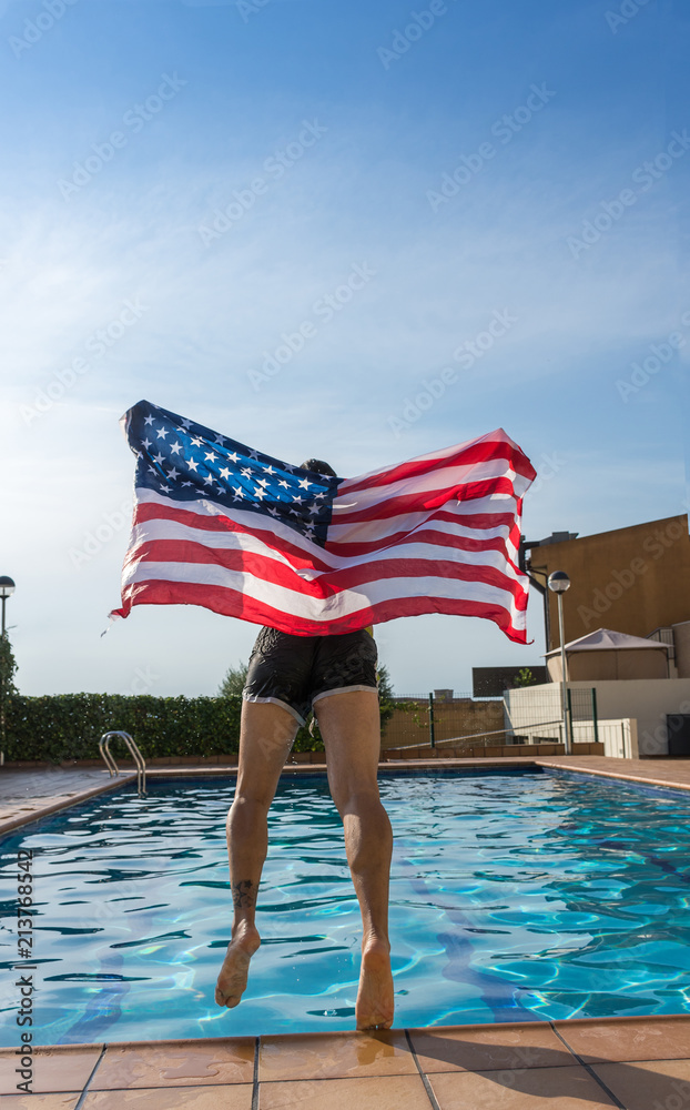 Foto de Man on vacation jumping to the pool with United states flag do ...