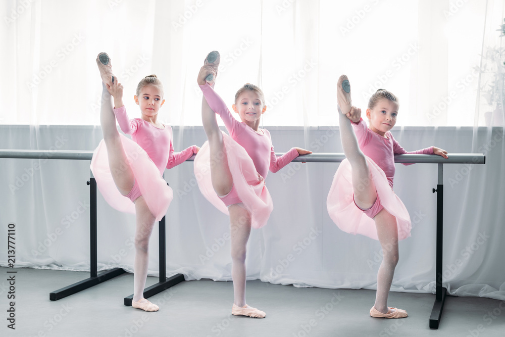beautiful little ballet dancers exercising and looking at camera in ...