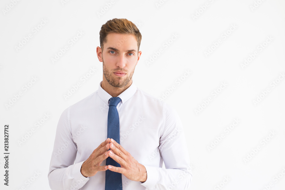Thoughtful business man holding hands together and looking at camera ...