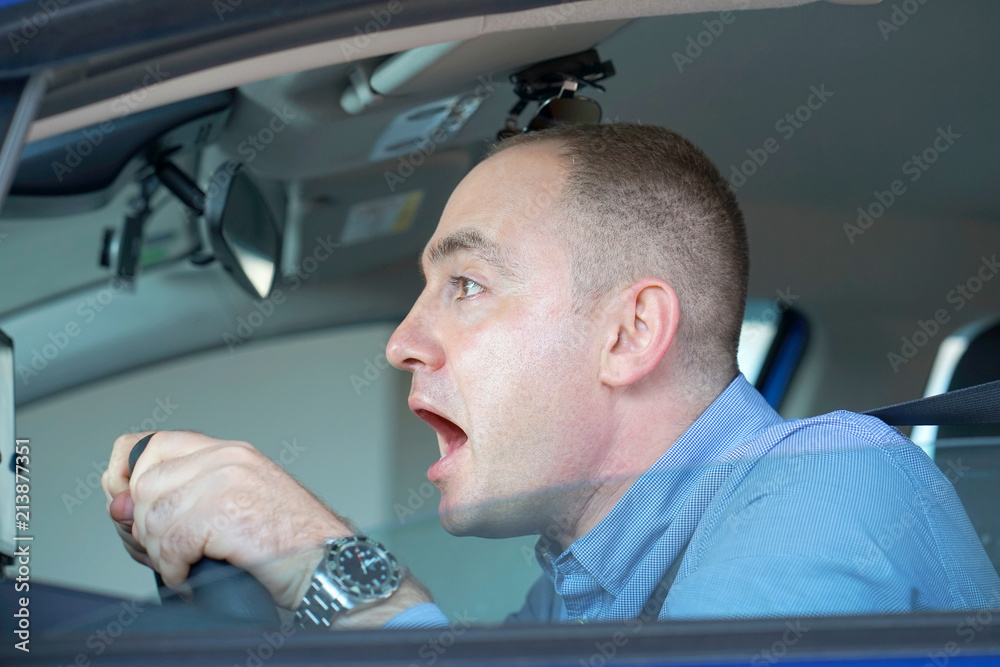 Side window view of inexperienced anxious motorist. Young man driving a ...