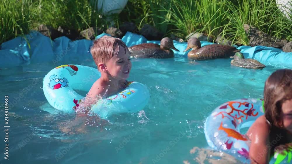 Two small children swim in a small pond. Brother and sister laughing ...