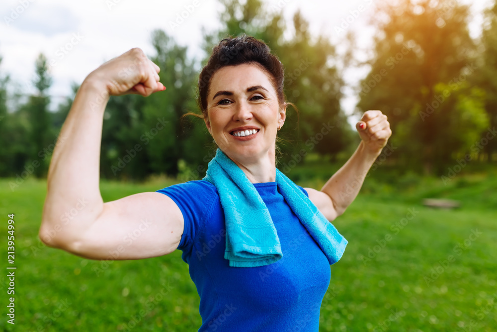 Smiling Senior woman flexing muscles outdoor in park. Elderly female ...