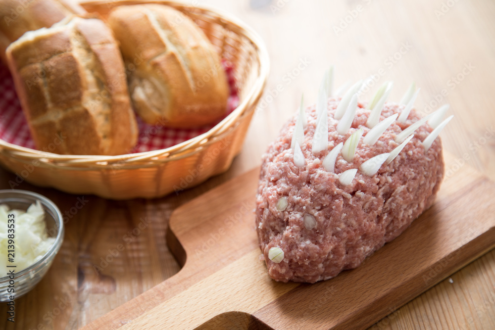 Mettigel aus Schweine Mett und Zwiebeln auf Holzbrett mit Brotkorb für ...