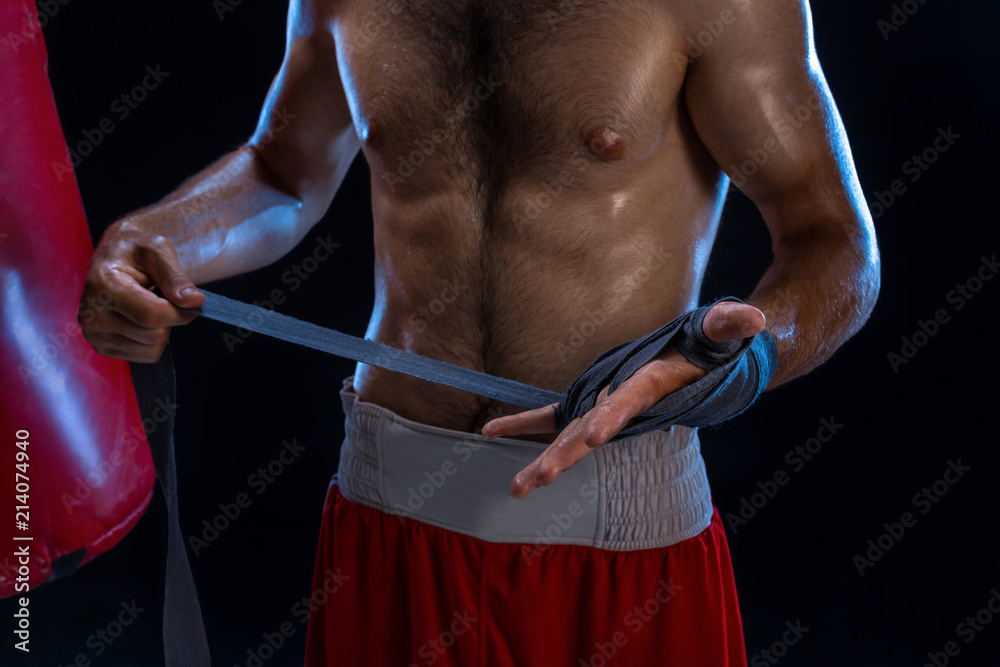 Close-up view on male hands of young athlete tying gray boxing bandages ...