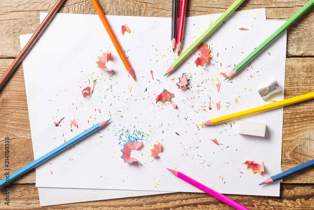 messy school table with white paper and wooden crayons. Top view of ...