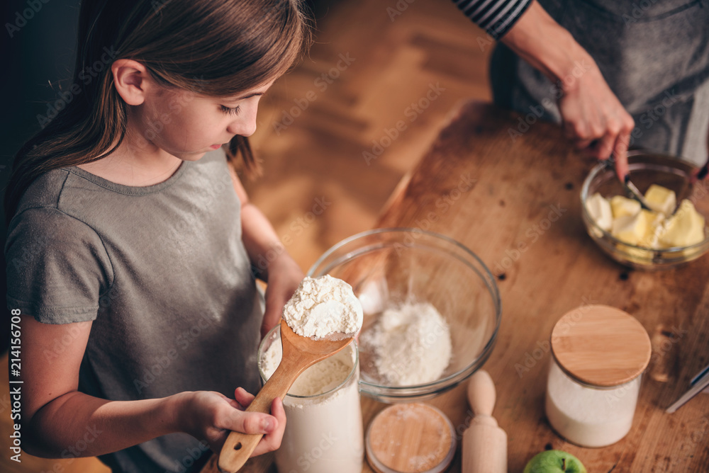 Girl adding flour into mixing bowl Stock Photo | Adobe Stock