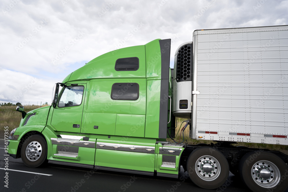 Profile of green big rig semi truck with refrigerated semi trailer on ...