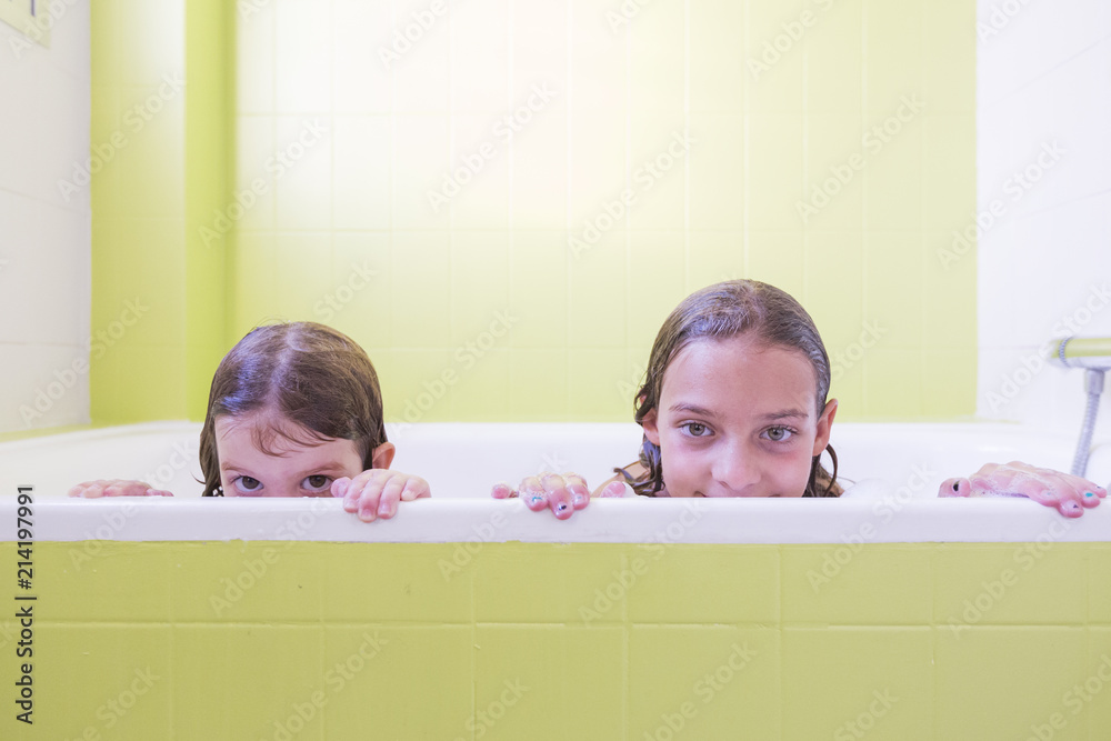 Happy laughing sister kids taking a bath playing with foam bubbles ...