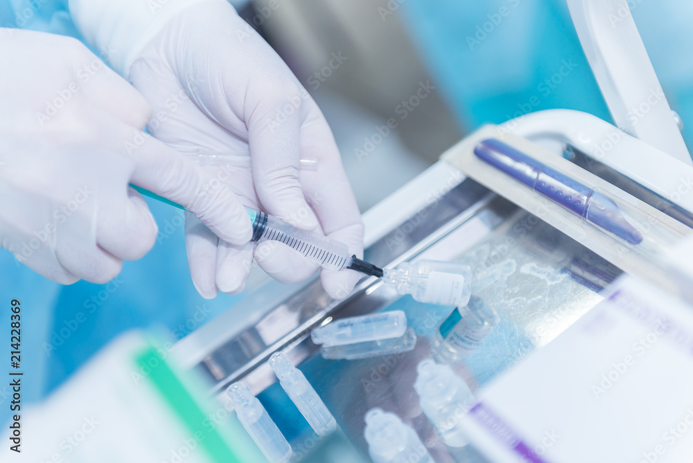 The hands of an anesthetist, who are taking medicine from the ampoule ...