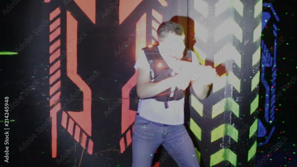 Excited young people aiming laser guns at other players during lasertag ...