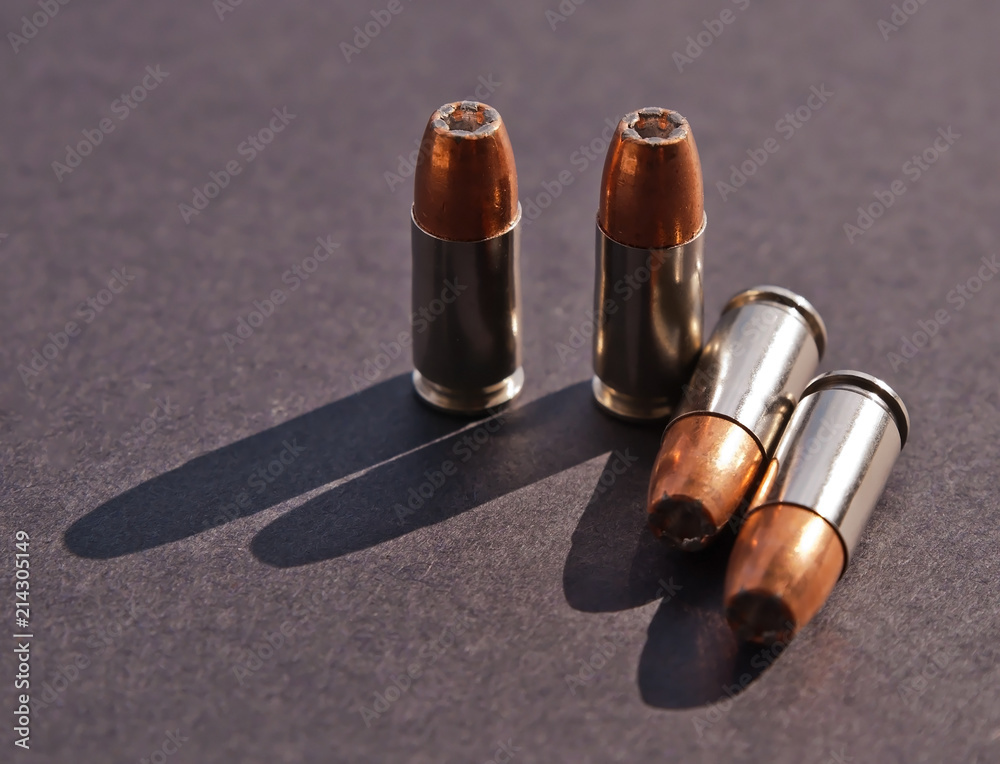 Four 9mm hollow point bullets casting shadows on a black background ...