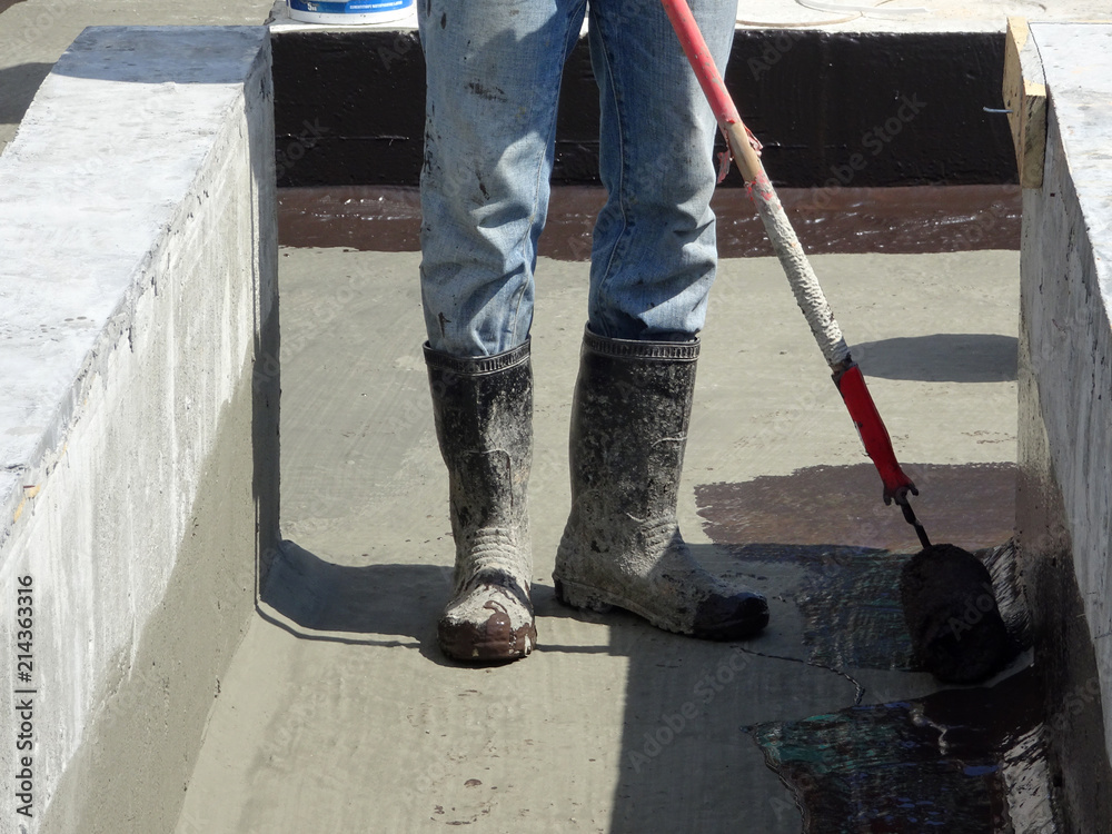 Waterproofing layer applied by construction workers on top of concrete ...
